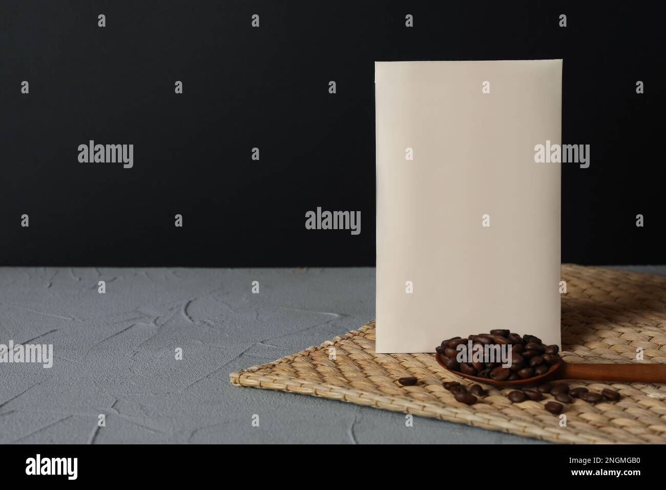 Scented sachet and coffee beans on grey table against black background ...