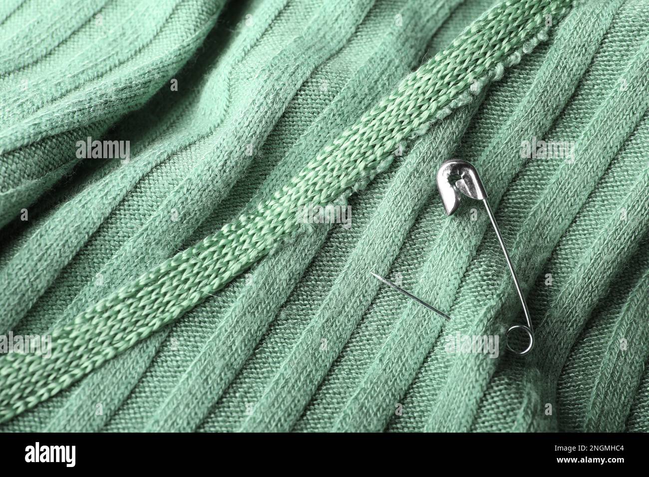 Metal safety pin on light green fabric, closeup Stock Photo - Alamy