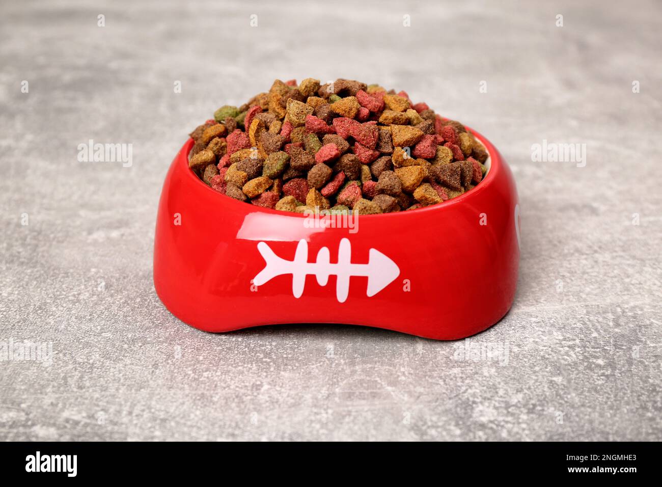 Dry cat food in red pet bowl on grey surface Stock Photo - Alamy