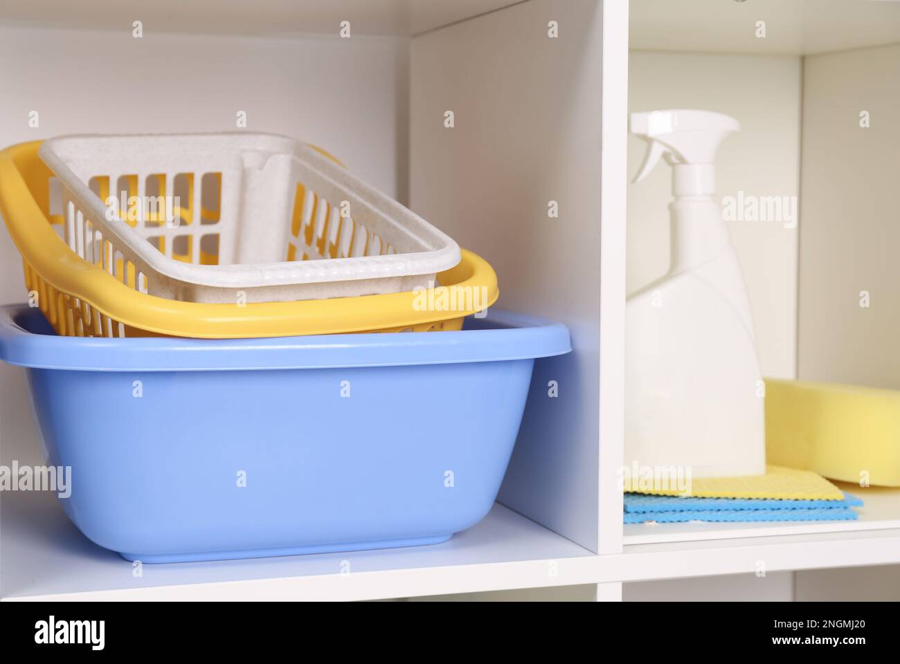 Detergent, baskets and different cleaning tools on shelves Stock Photo ...