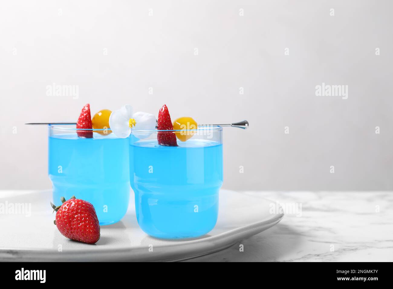 Bright light blue cocktail in glasses on white marble table, space for ...