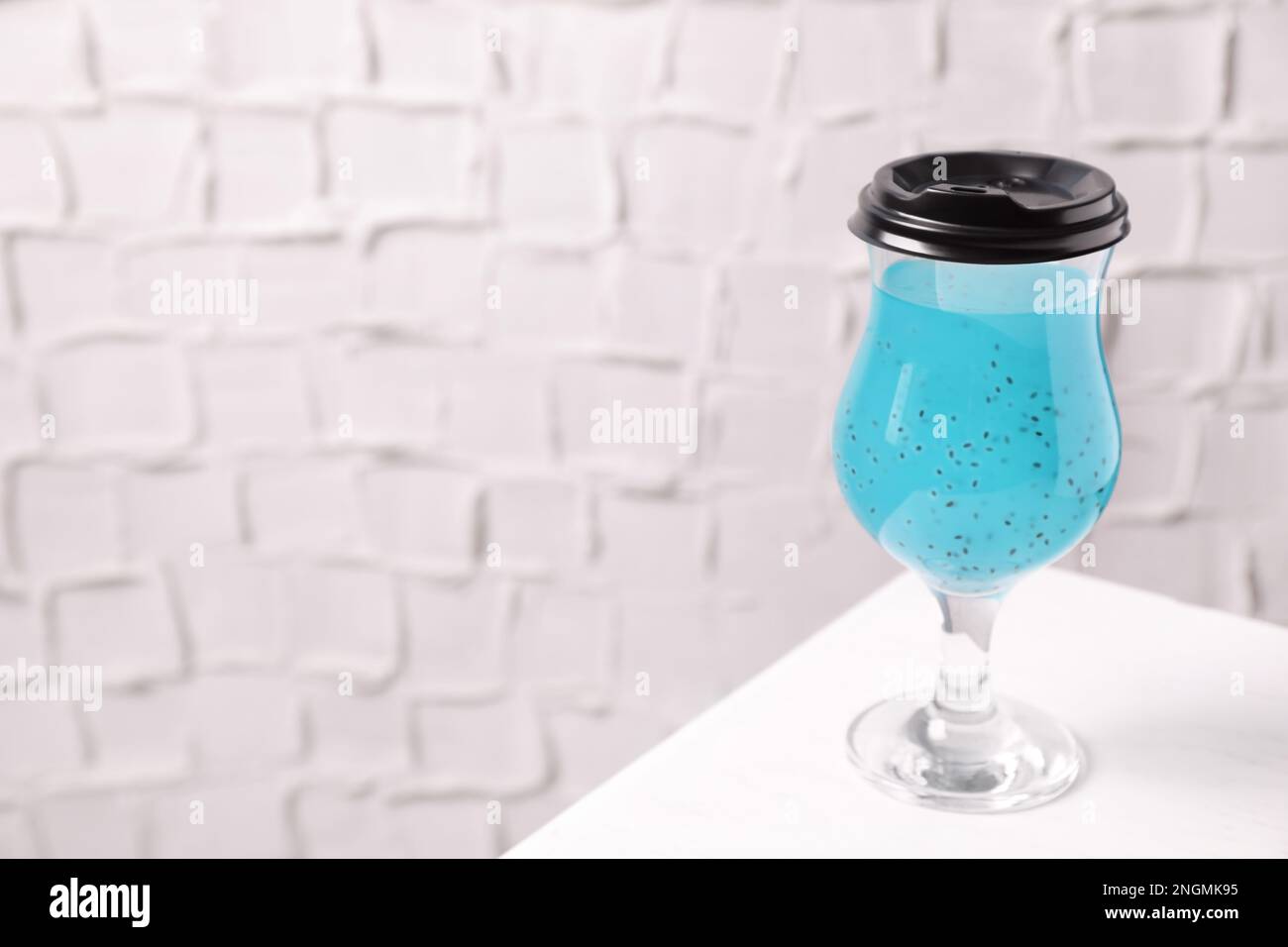 Light blue drink in glass with lid on white table, space for text Stock ...