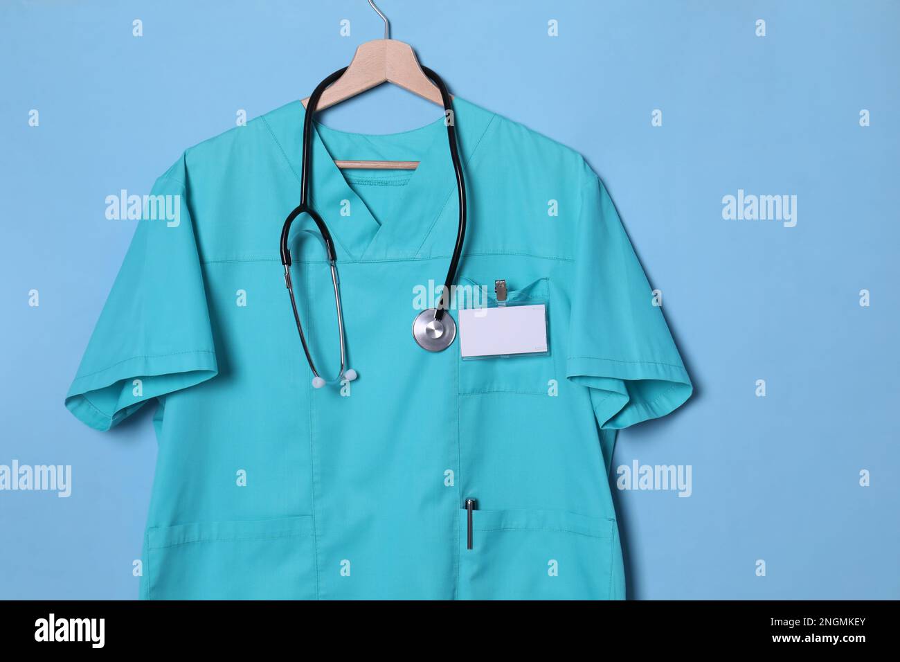 Turquoise doctor shirt with stethoscope and badge hanging on light blue ...