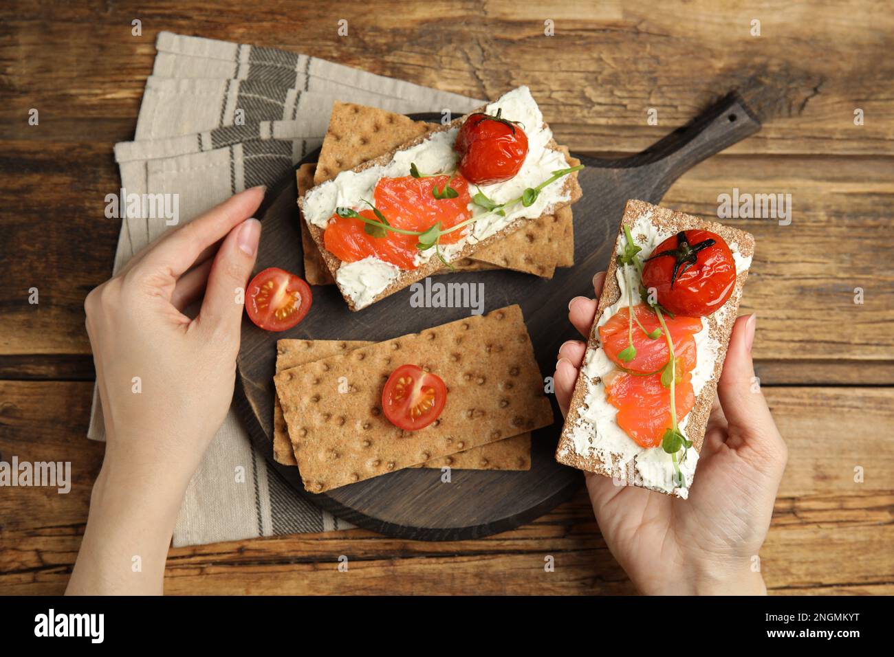 Woman eating fresh rye crispbreads with salmon, cream cheese and ...