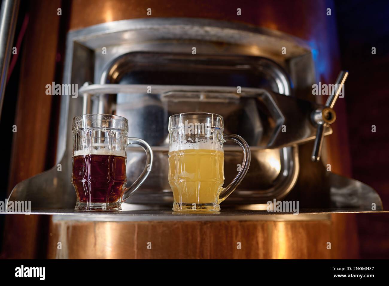 Freshly made craft light and dark beer in glass mug standing on barrel ...