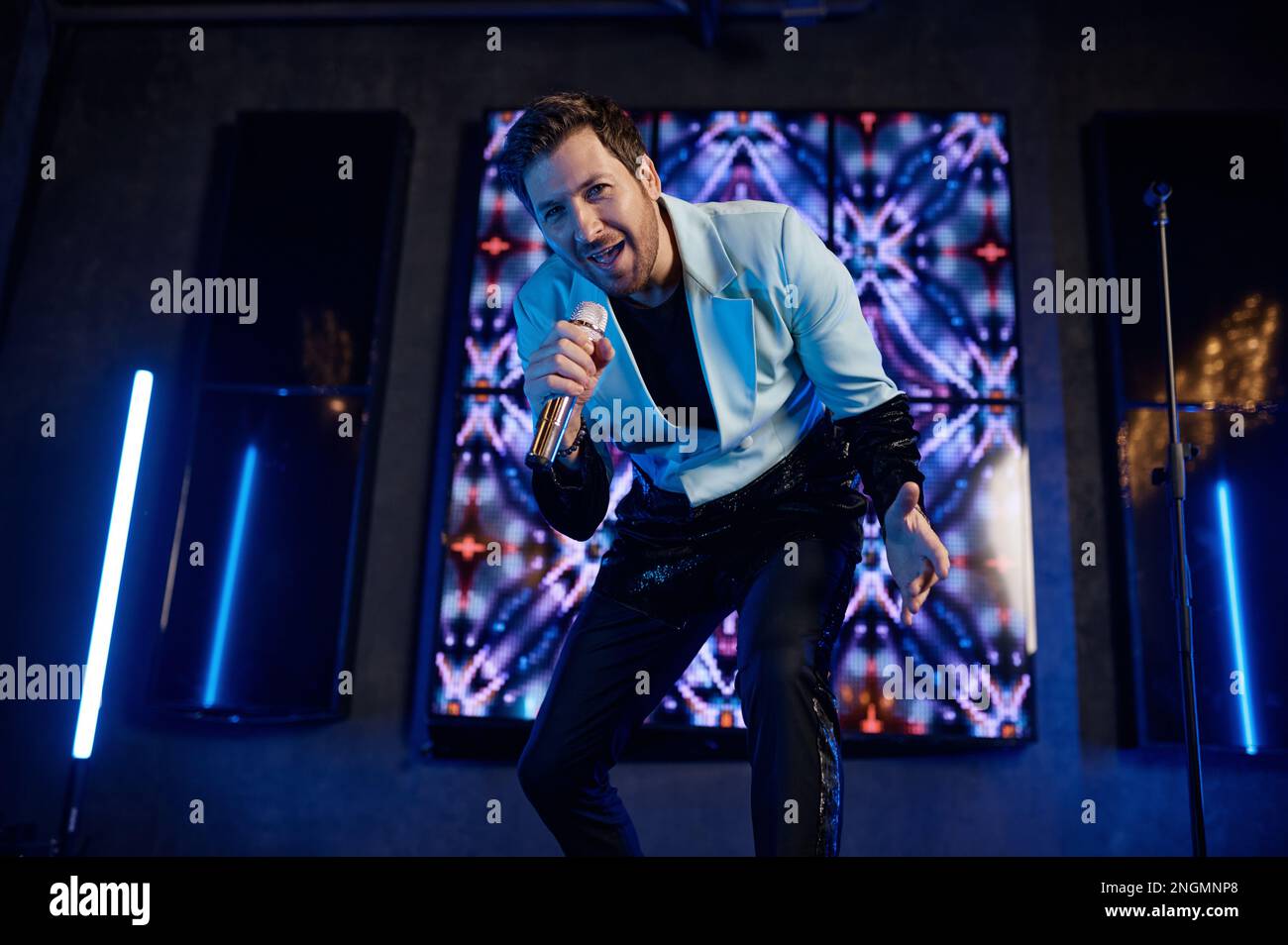 Man with enthusiastic face holding microphone and singing song on stage ...
