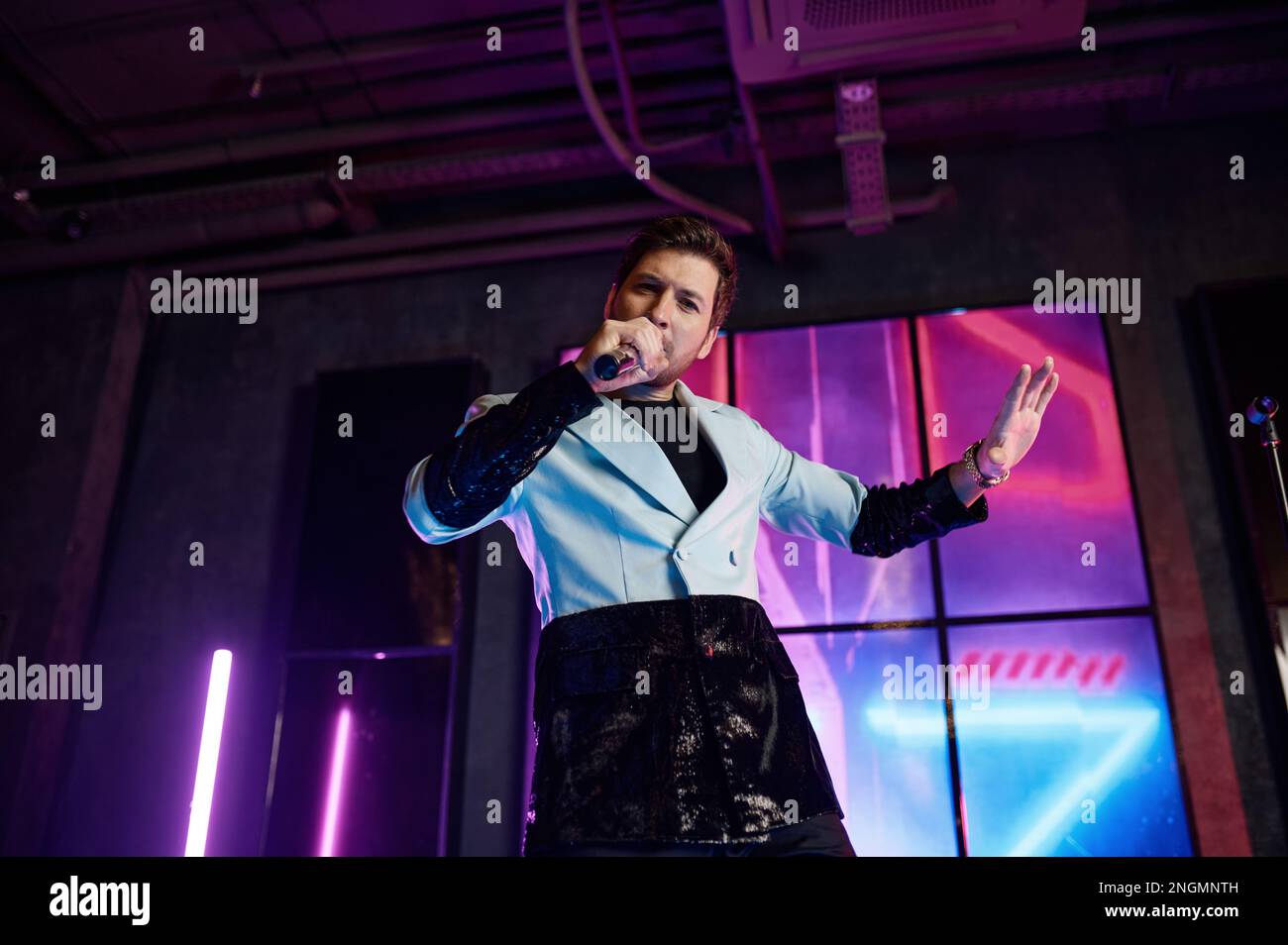 Male singer holding microphone standing and performing on stage Stock ...