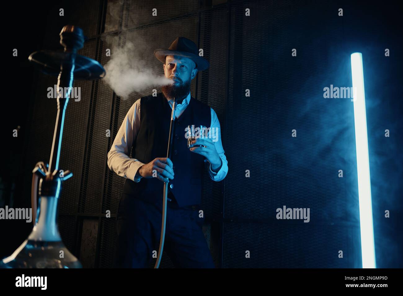 Front view of resting man smoking hookah at home workplace with neon ...