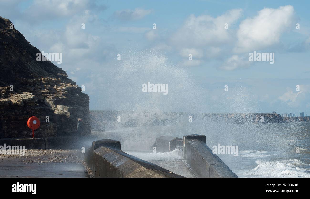 Heavy seas crash into the promenade throwing up great columns of spray ...