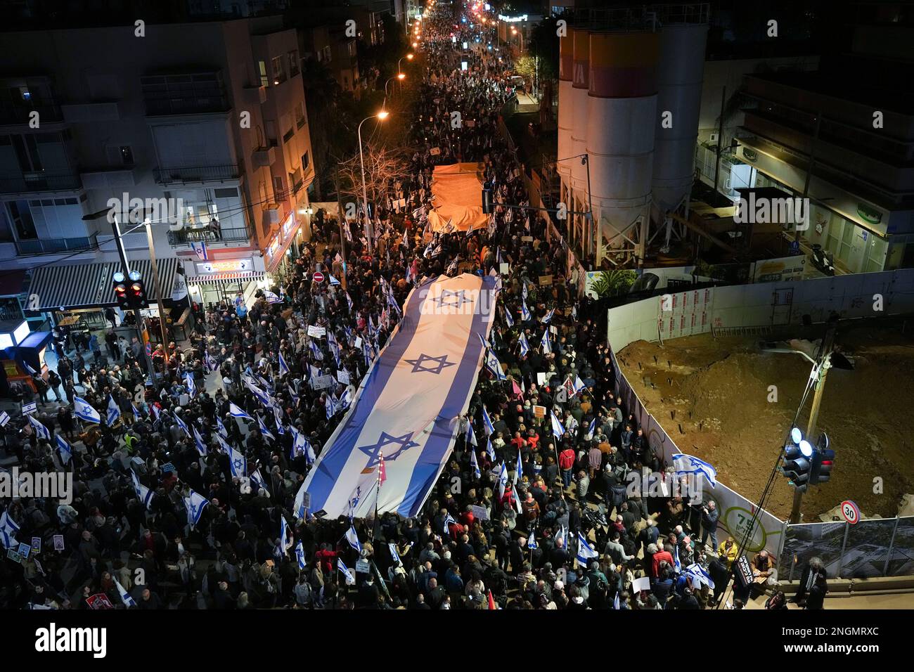 Israelis march with large national flag during a protest against plans ...