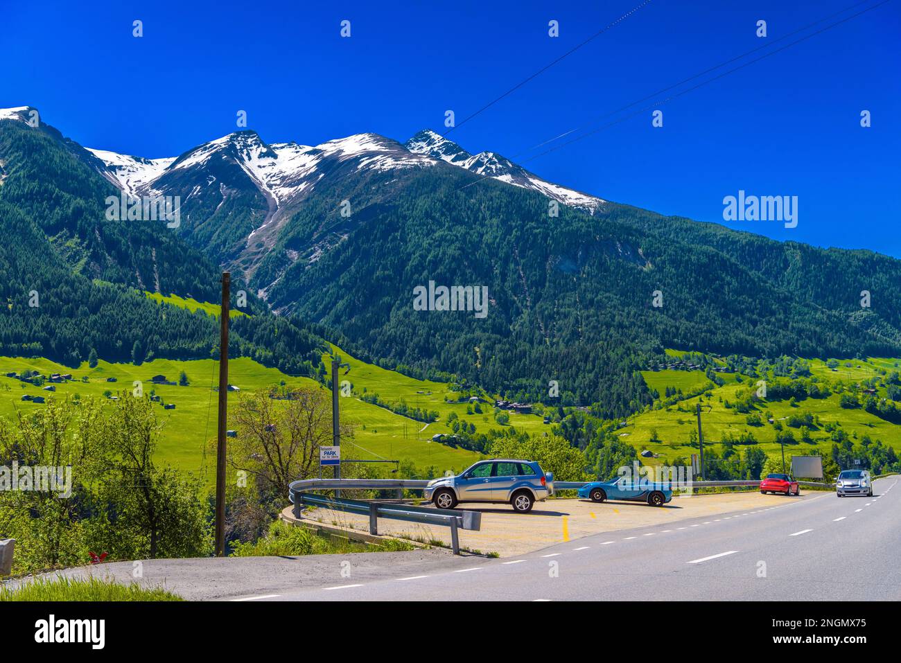 Cars on the road in Alp mountains with forest and fields, Fiesch, Goms ...