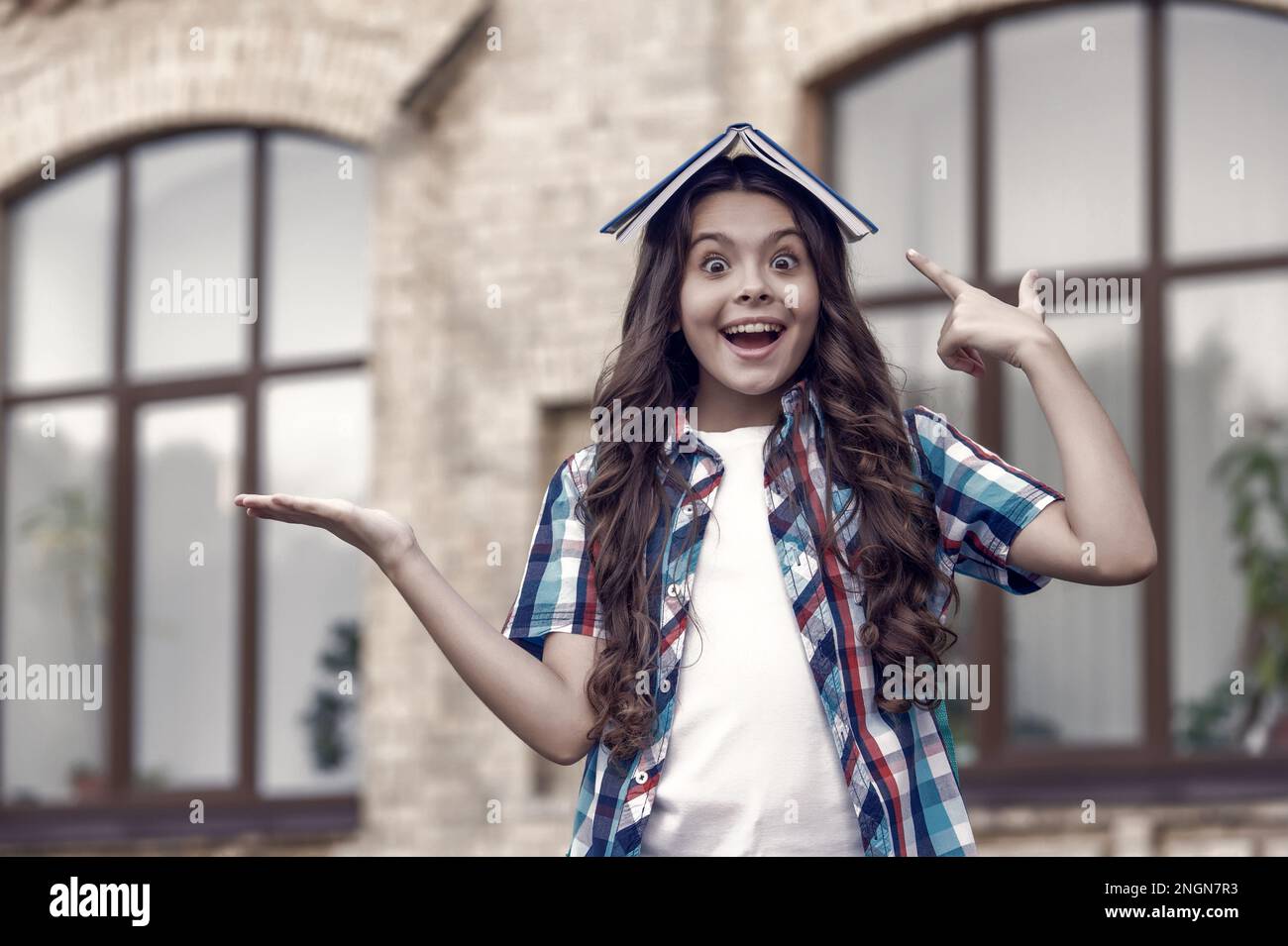 Bestselling product. Happy kid hold open hand pointing at book on head ...