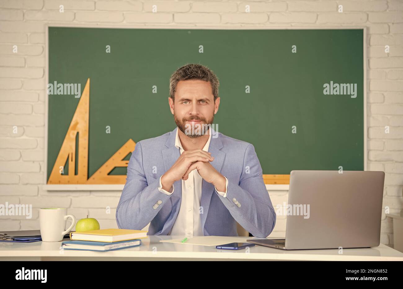 smiling school teacher in classroom with laptop at blackboard Stock ...