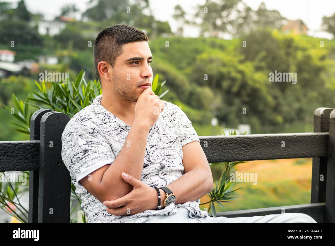 young Latino man, thinking and looking for new ideas, sitting on a ...