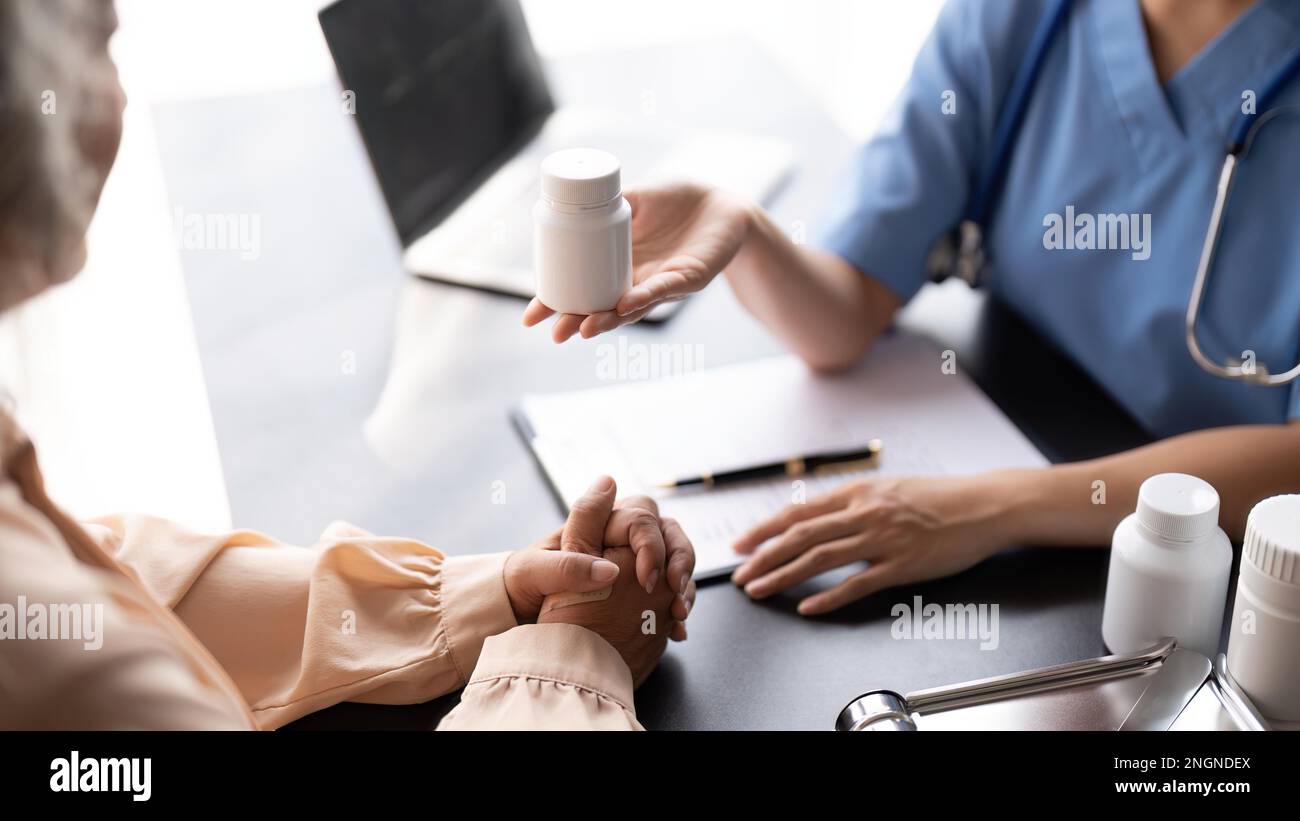 Young nursecaregiver advising contented senior woman on medication in ...
