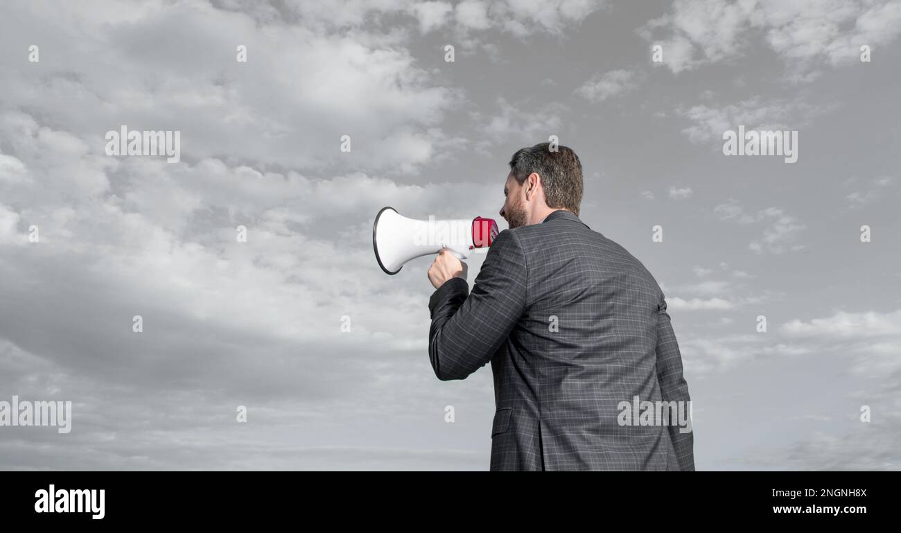 back view of businessman shout in loudspeaker on sky background. copy ...