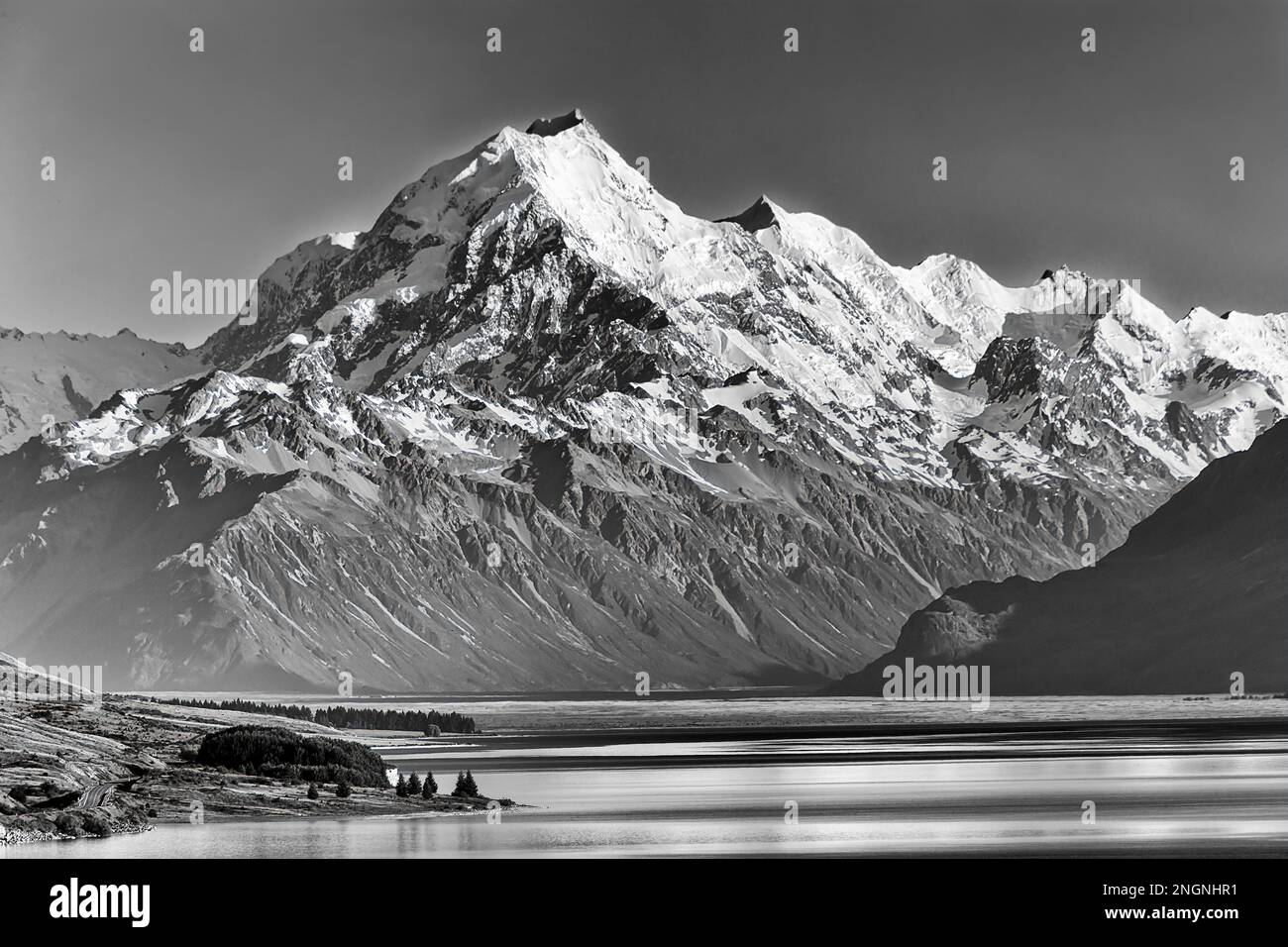 Dramatic black-white majestic Mt Cook rocky snow capped peak over Lake ...