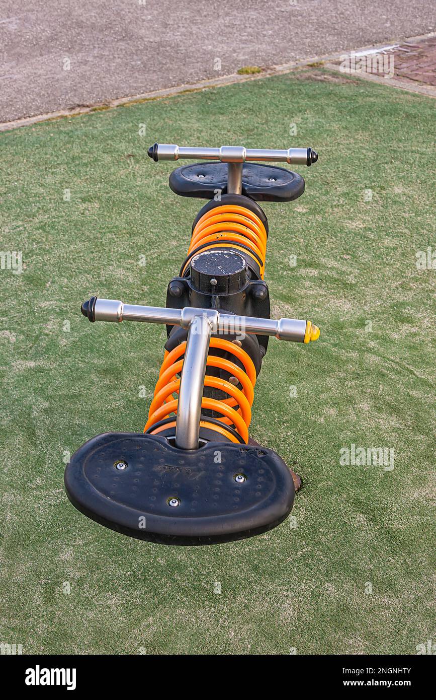 playground seesaw with two black plastic seating with orange steel ...