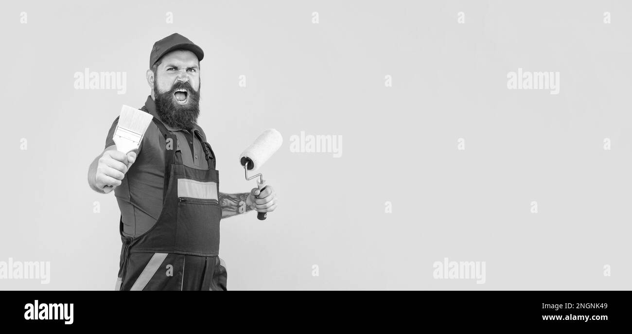 angry shouting bearded man renovator in work clothes hold paint roller ...