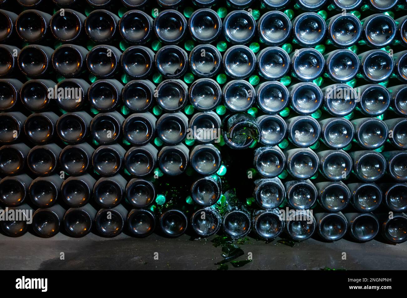 Сracked glass bottle in pile of champagne bottles during of traditional ...