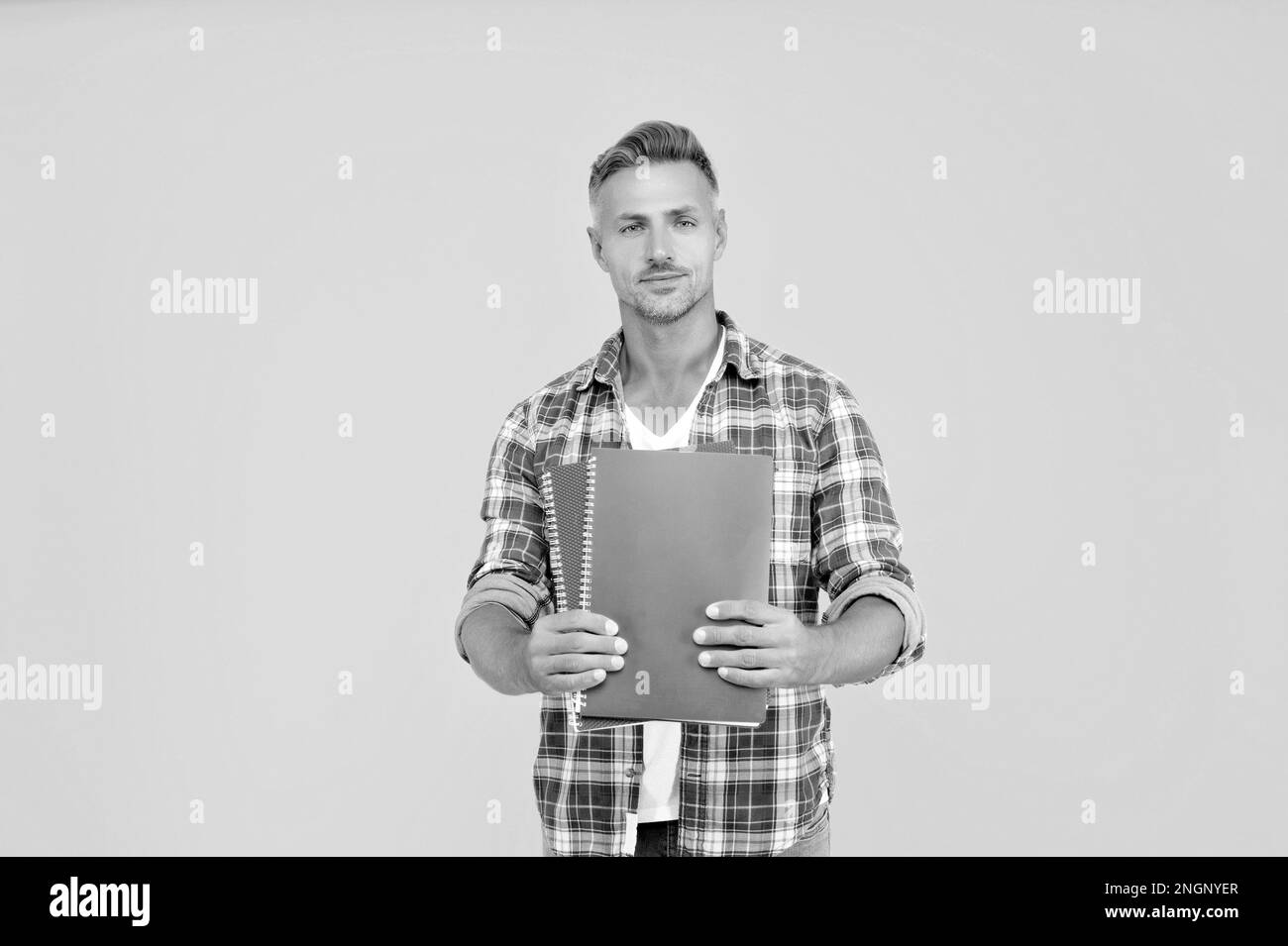 Serious university student holding books for education yellow ...