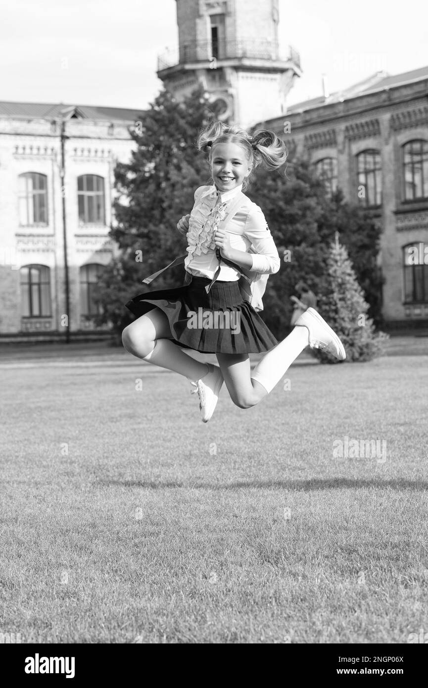 Happy energetic child in uniform back to school jumping for joy ...
