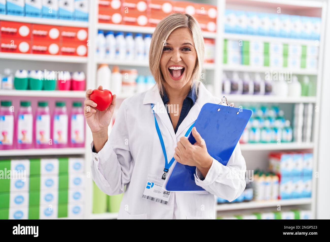 Young woman working at pharmacy drugstore holding heart smiling and ...