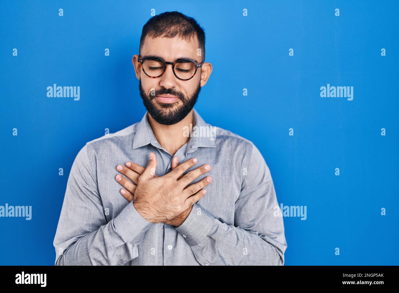Middle east man with beard standing over blue background smiling with ...