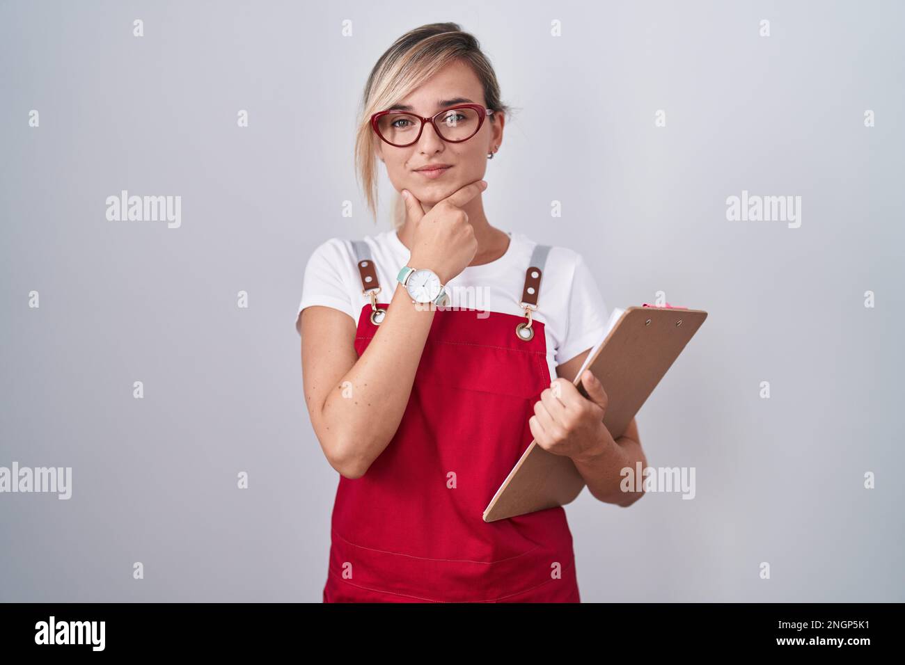 Young blonde woman wearing waiter uniform holding clipboard looking ...