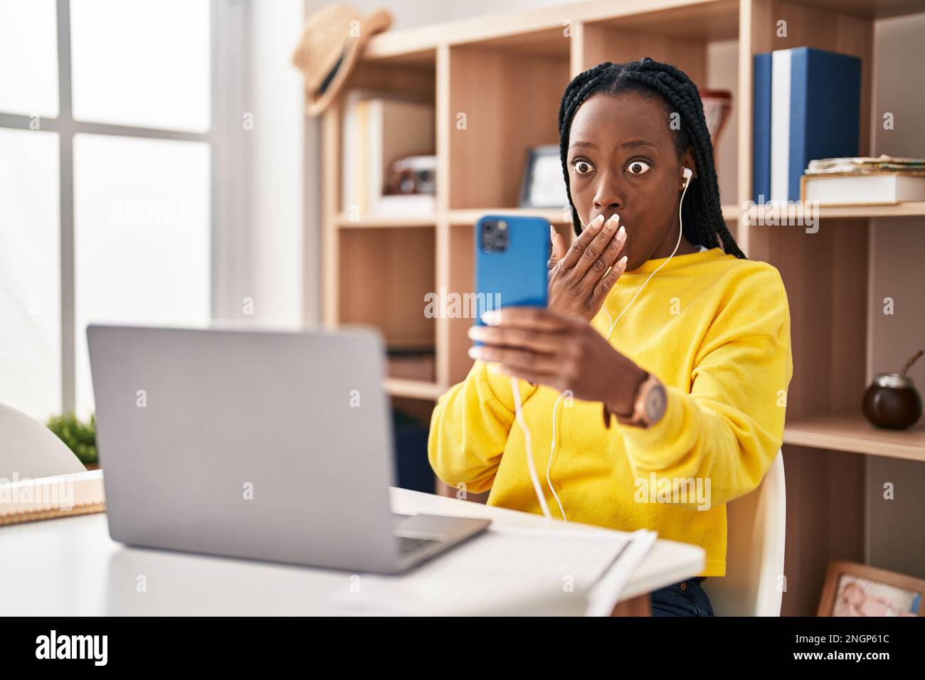Beautiful black woman doing video call with smartphone covering mouth ...