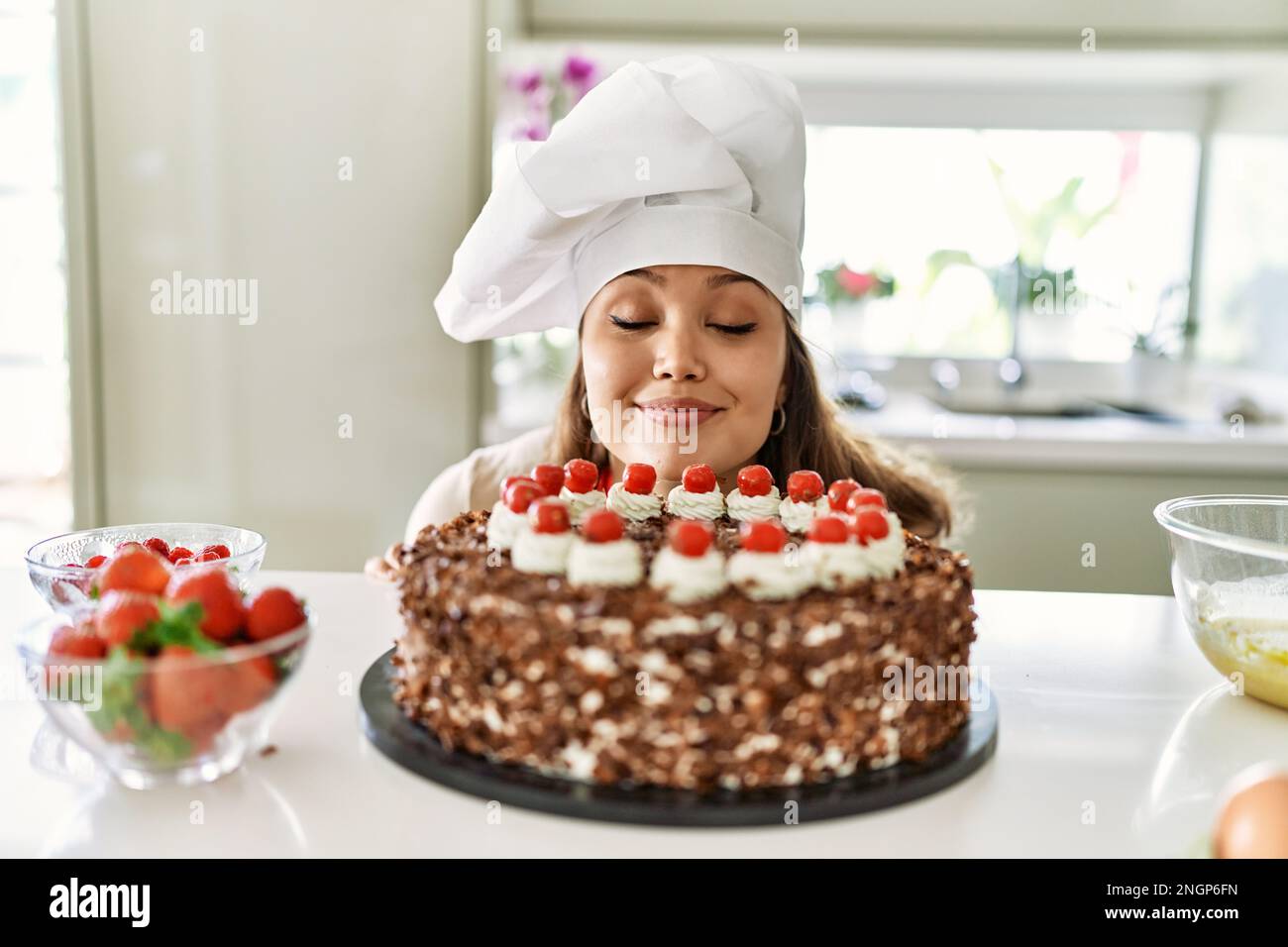Young beautiful hispanic woman smiling confident smelling cake at the ...