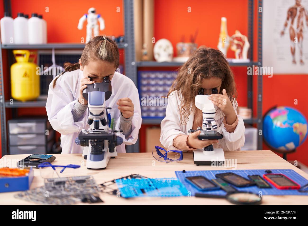 Two kids students using microscopes standing at laboratory classroom ...