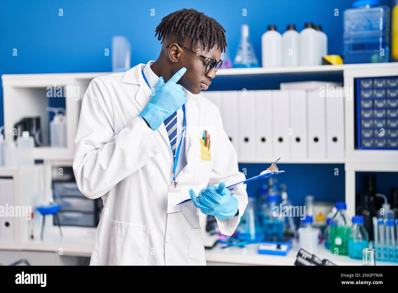 African american man scientist reading report with doubt expression at laboratory Stock Photo ...
