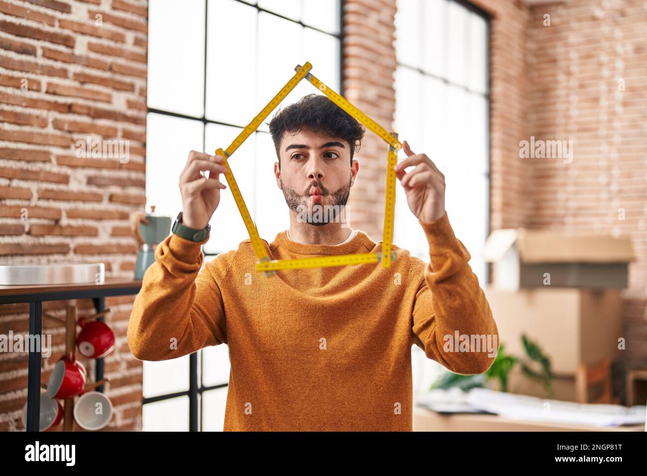 Hispanic man with beard moving to a new home holding ruler making fish ...