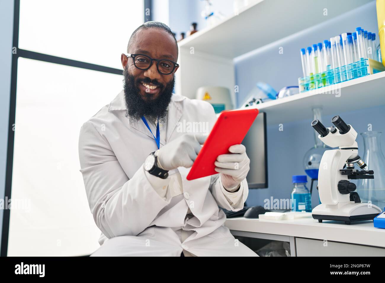 Young african american man wearing scientist uniform using touchpad at ...