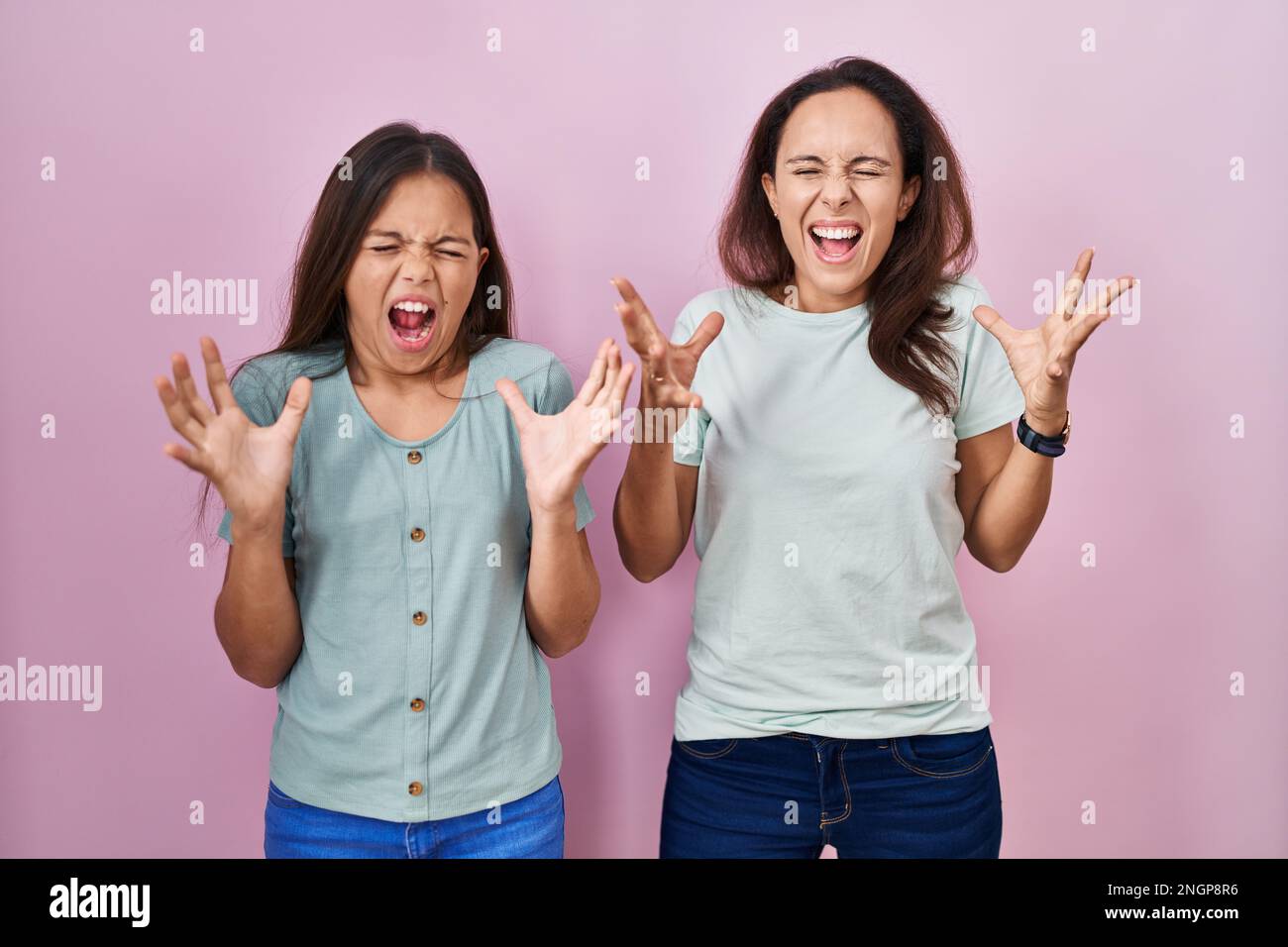 Young Mother And Daughter Standing Over Pink Background Celebrating Mad
