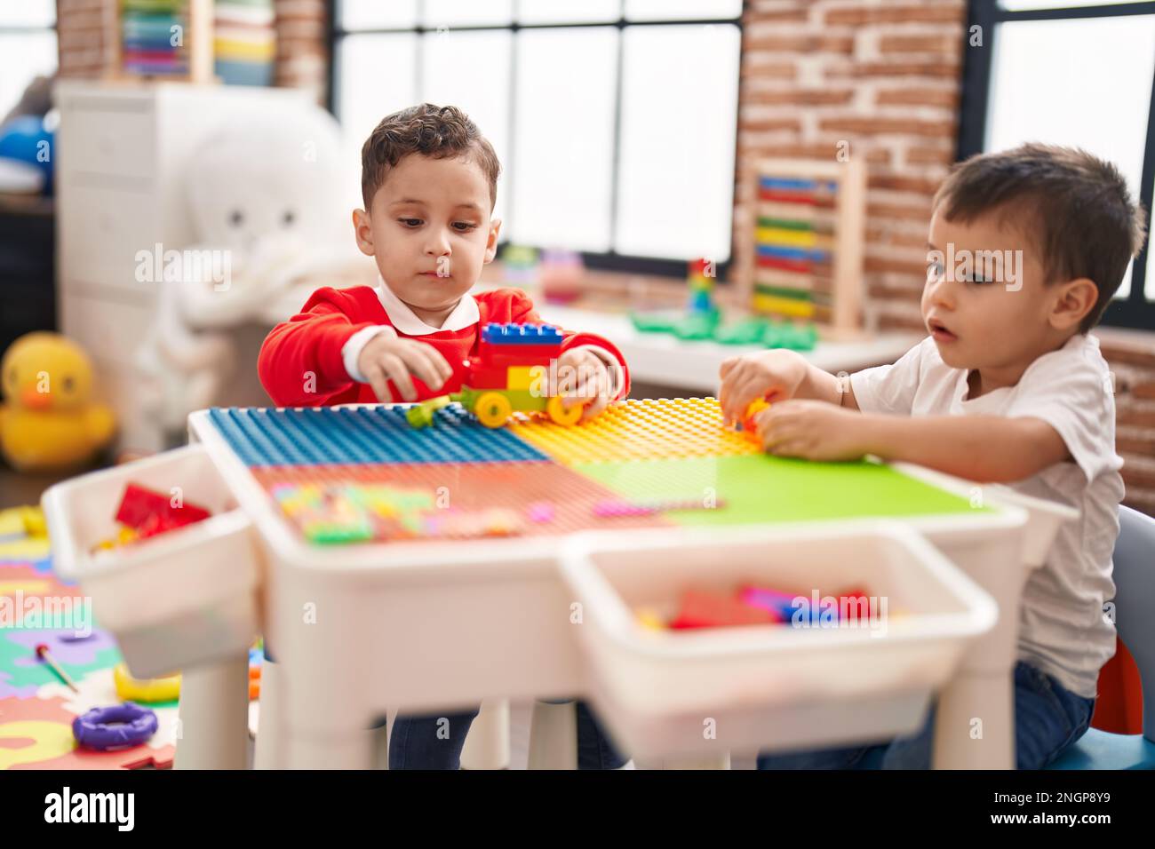 Two kids playing with construction blocks sitting on table at ...