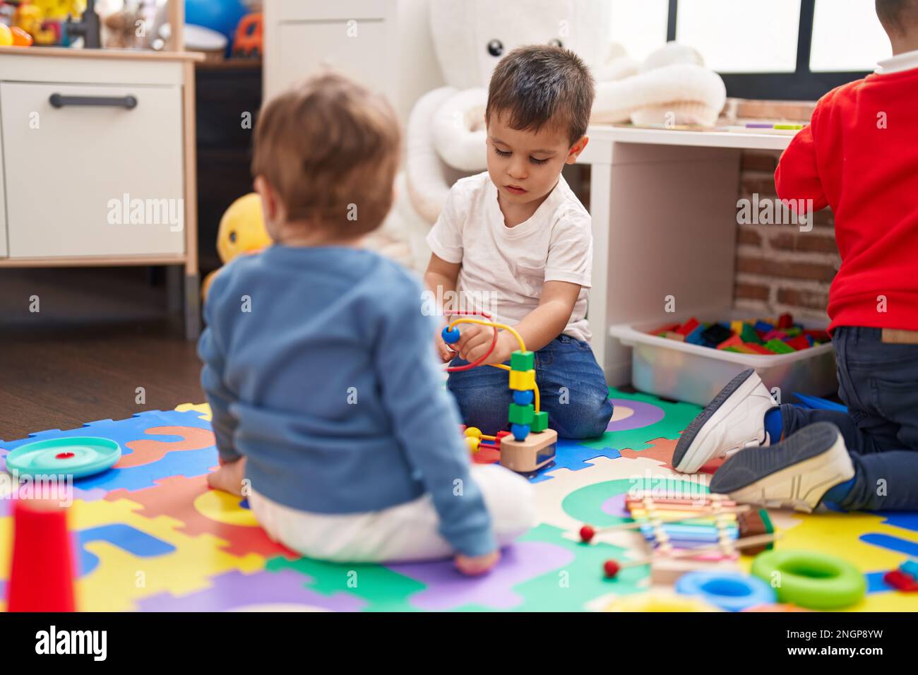 Group of kids playing with toys sitting on floor at kindergarten Stock ...