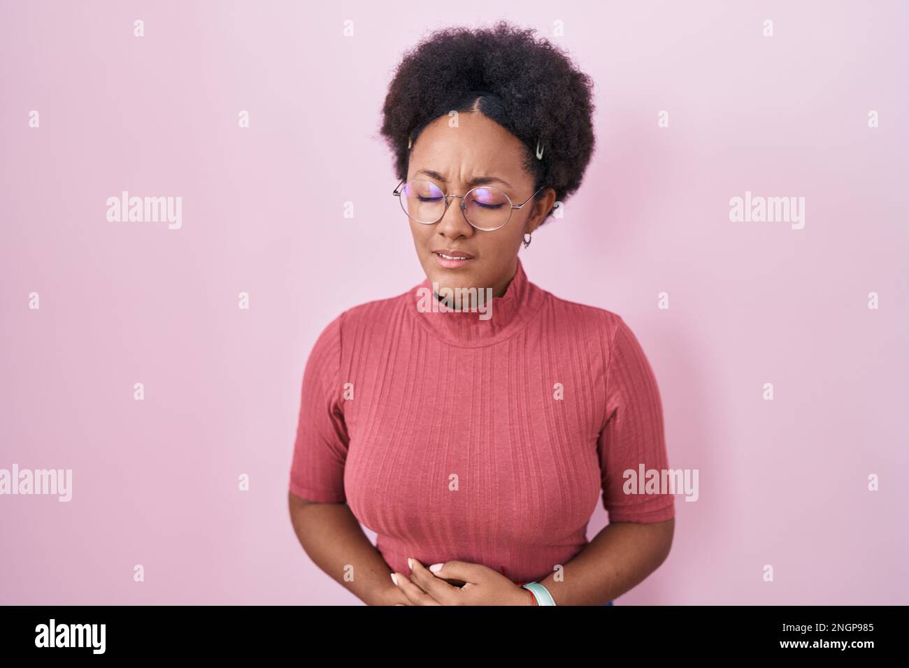 Beautiful african woman with curly hair standing over pink background ...