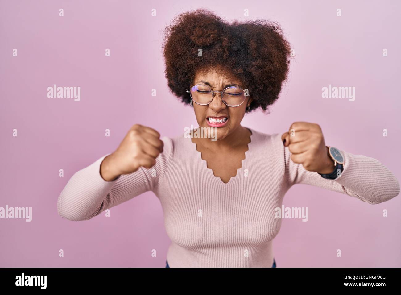 Young african american woman standing over pink background angry and ...