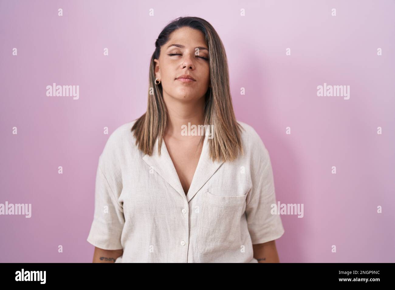 Blonde woman standing over pink background looking sleepy and tired ...