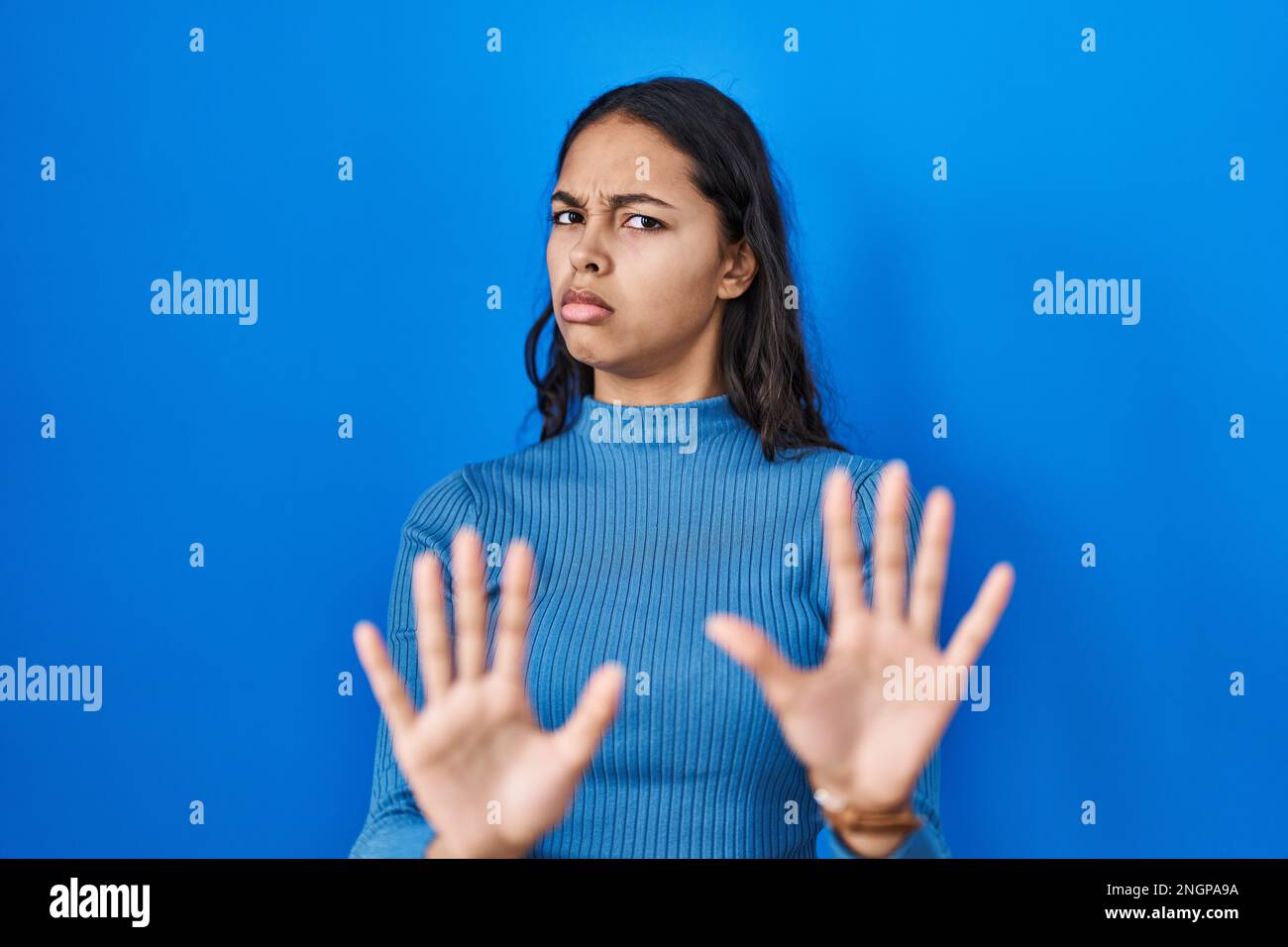 Young brazilian woman standing over blue isolated background moving ...