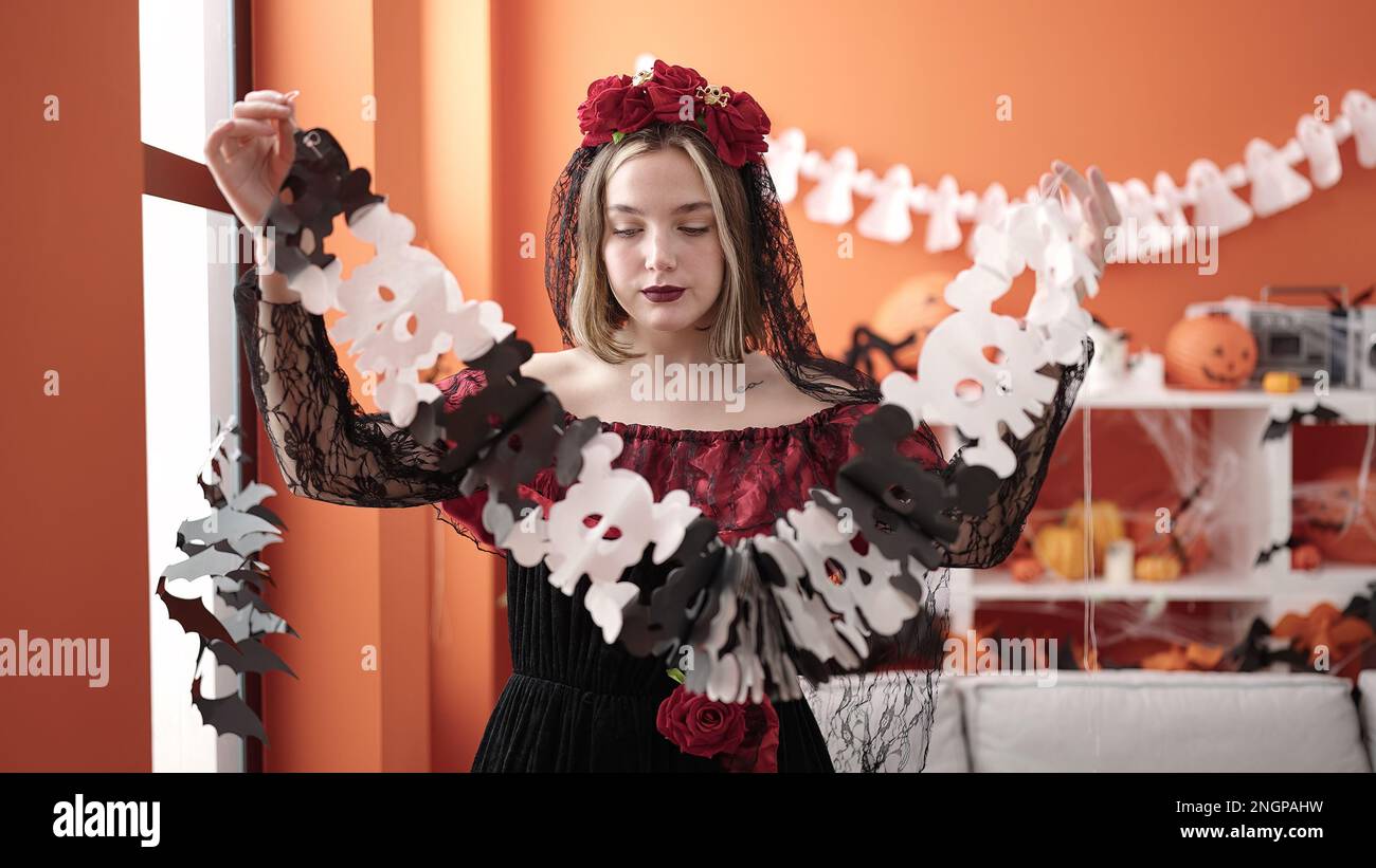 Young blonde woman wearing katrina costume decorating halloween party ...