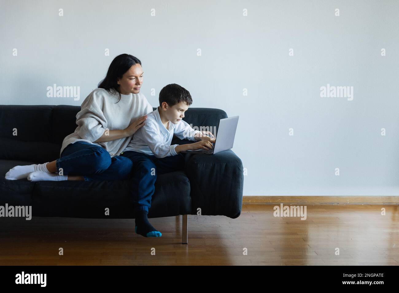 mother and son use laptop, online classes at home on the couch Stock ...