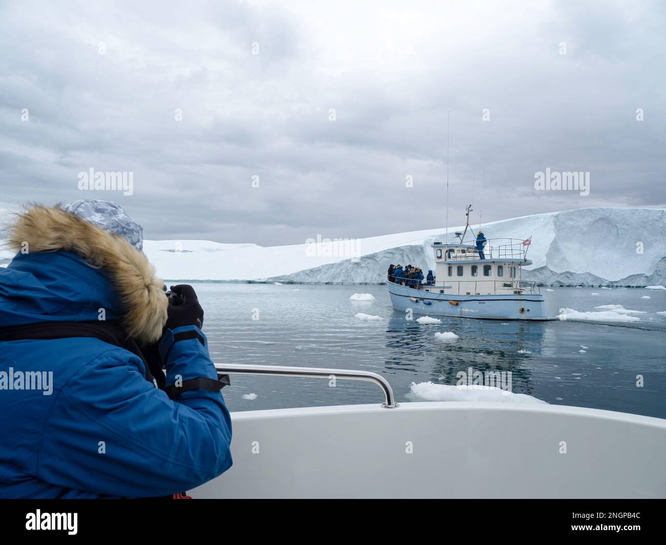 Tourists taking an ice tour in a small boat watching icebergs from the ...