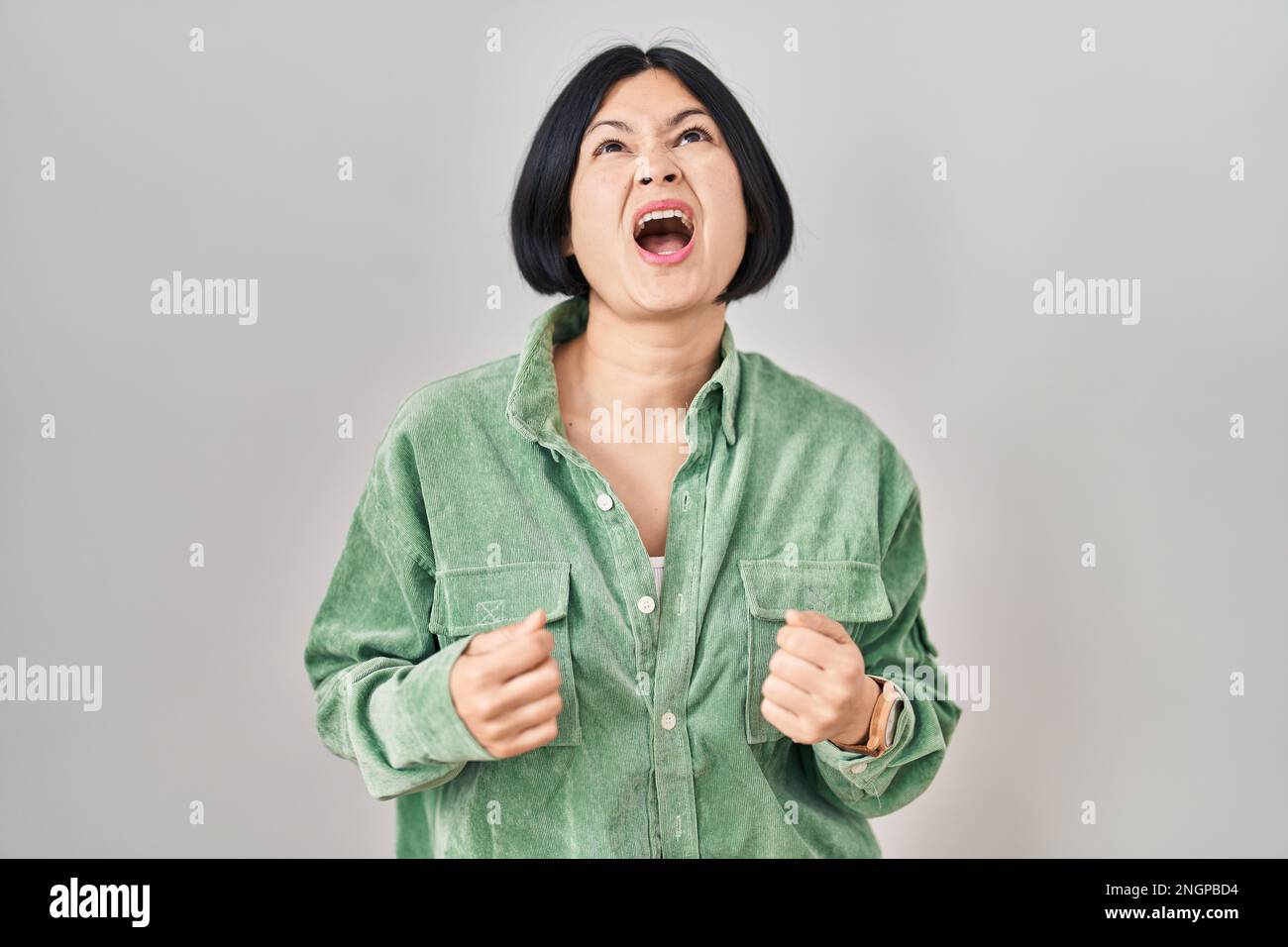 Young asian woman standing over white background angry and mad ...