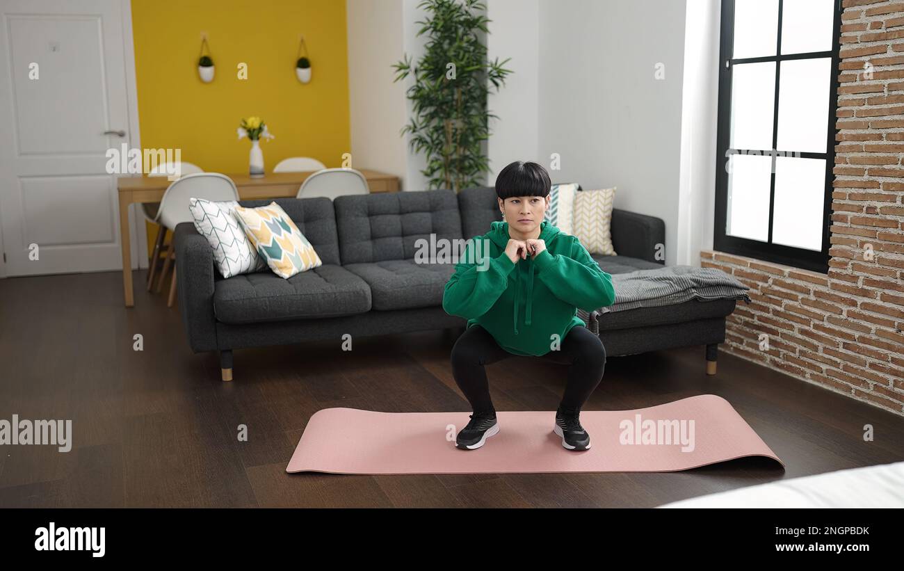 Young chinese woman training legs exercise standing at home Stock Photo ...