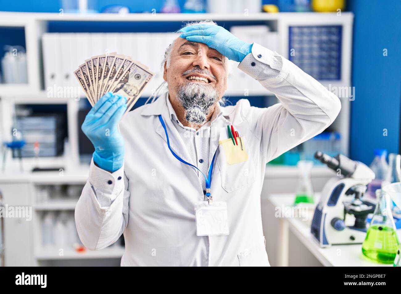 Middle age man with grey hair working at scientist laboratory holding ...