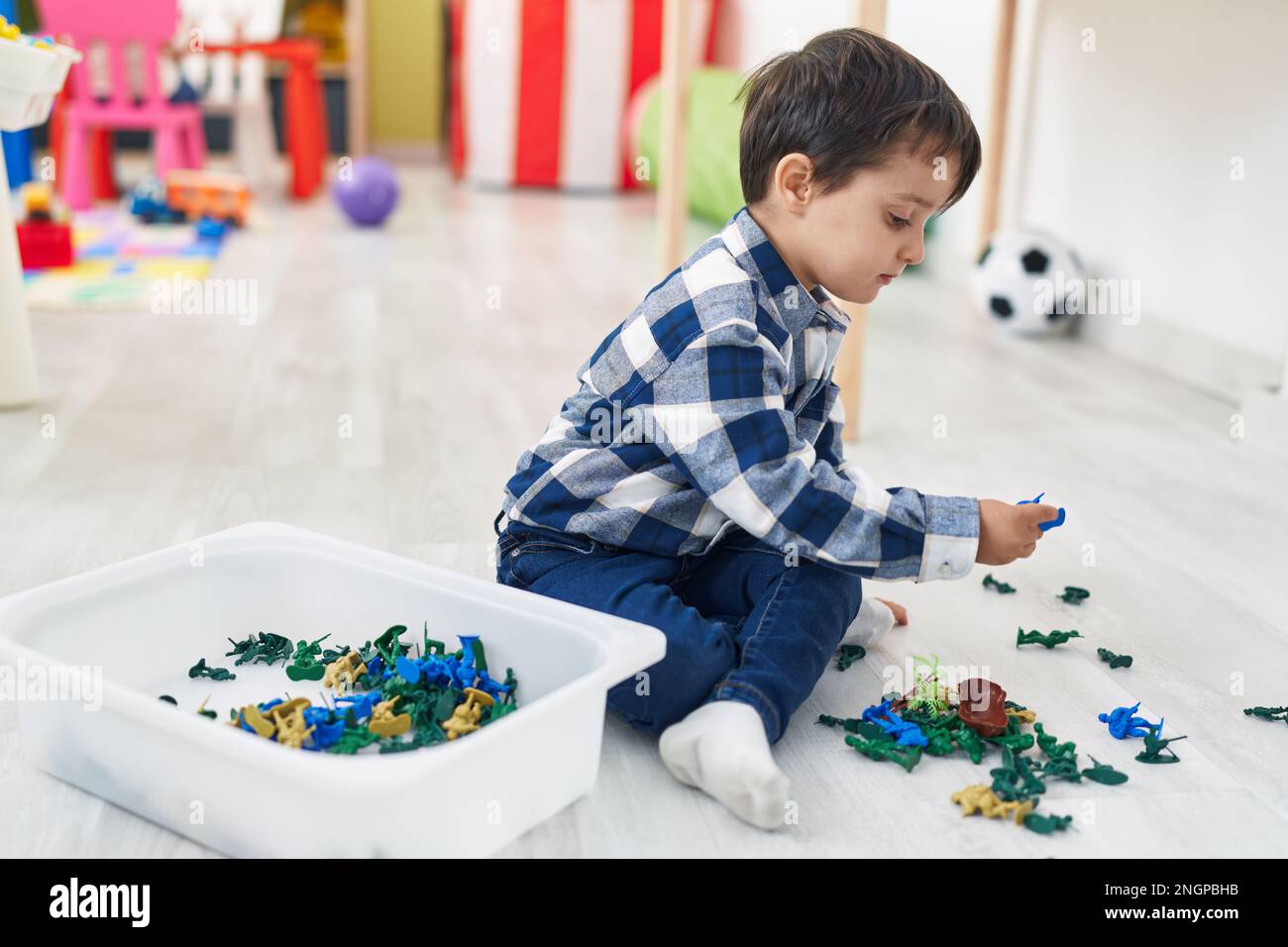 Adorable hispanic boy playing with soldiers toy sitting on floor at ...