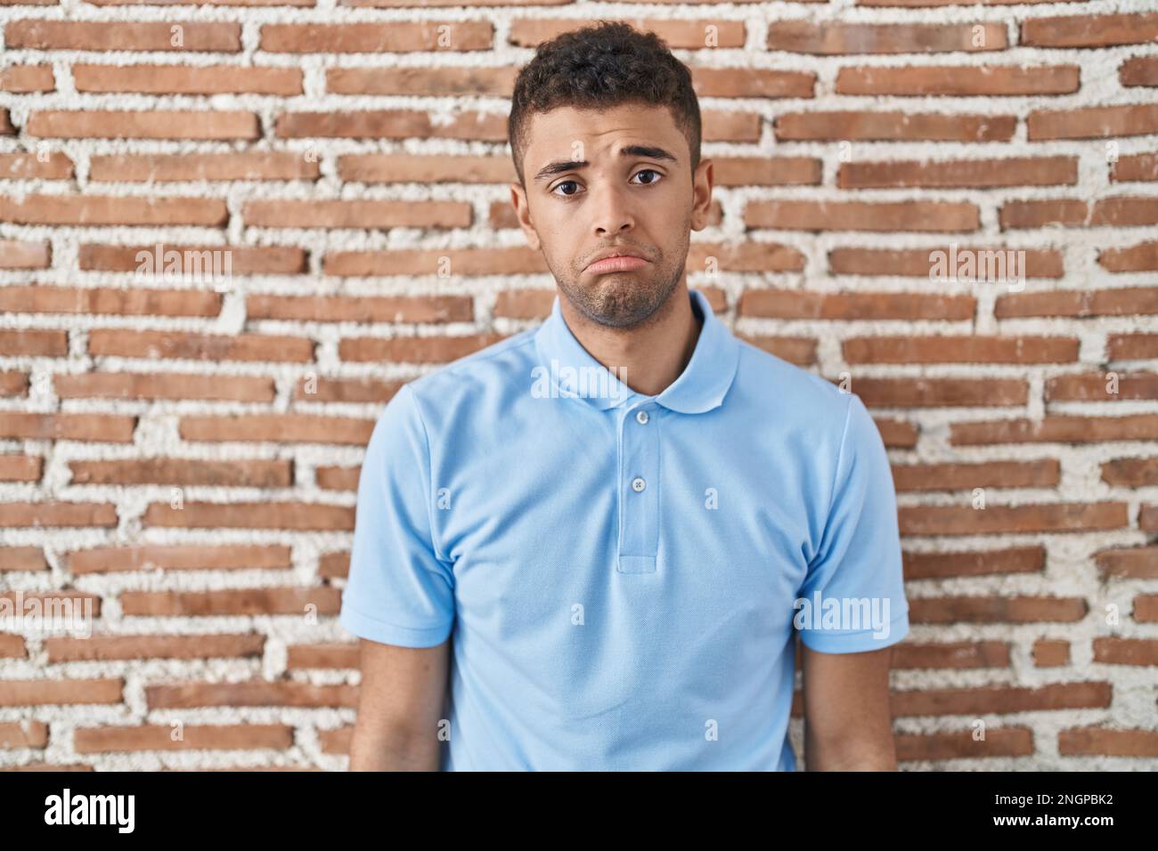 Brazilian young man standing over brick wall depressed and worry for ...